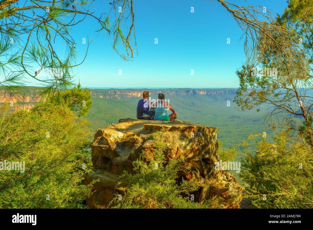 Unidentifiable couple sitting on a huge boulder and looking panoramic ...