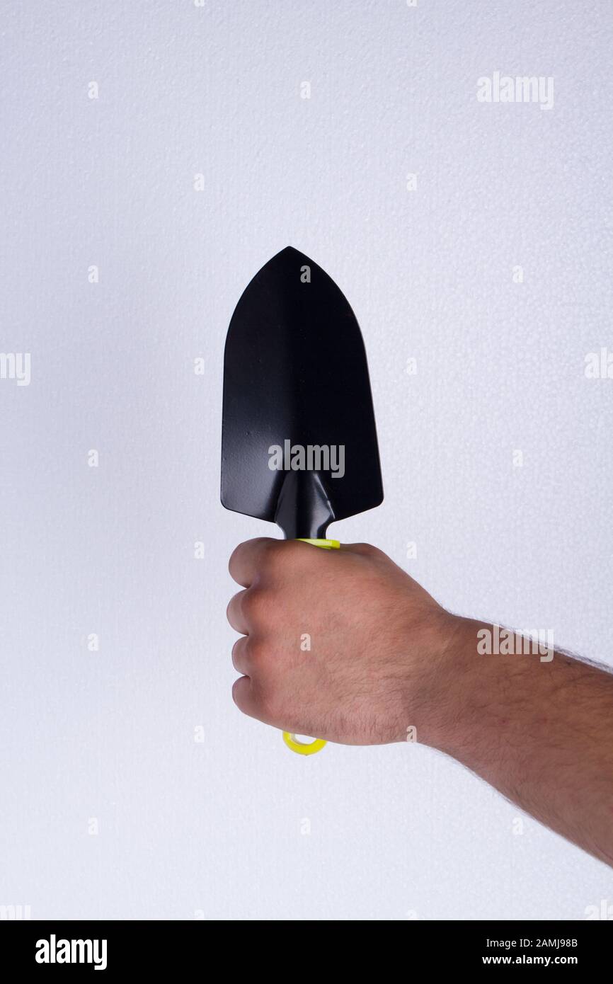 Male gardener's hand with black steel trowel Stock Photo - Alamy