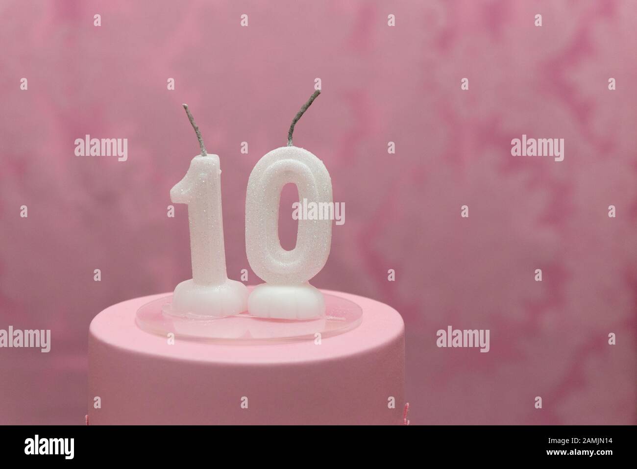 Birthday cake with candles as number ten on pink arabesques background ...