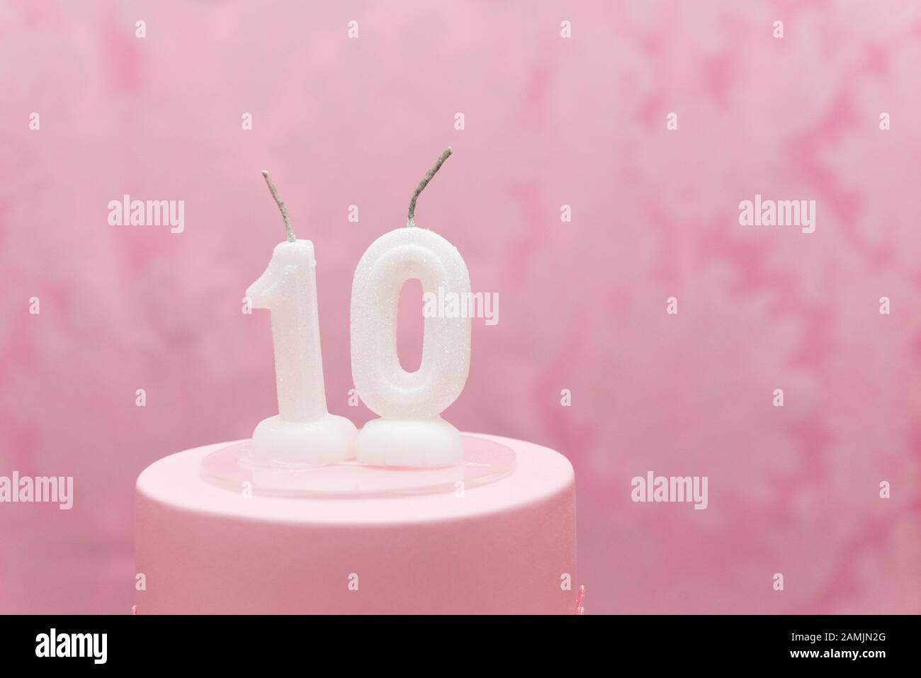Birthday cake with candles as number ten on pink arabesques background ...