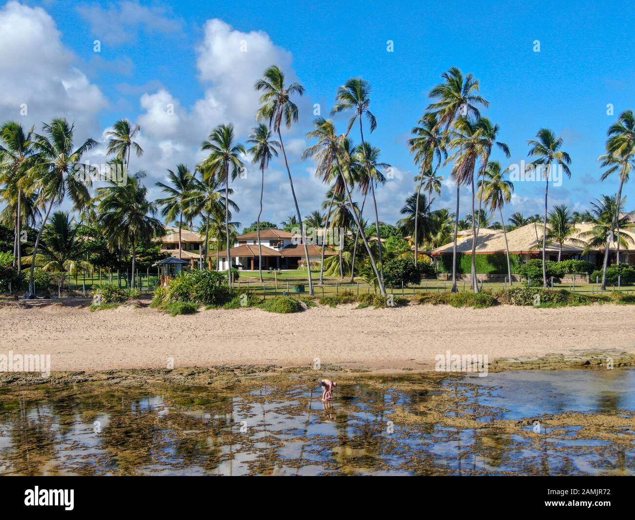 Aerial view of tropical white sand beach with people enjoying the water ...