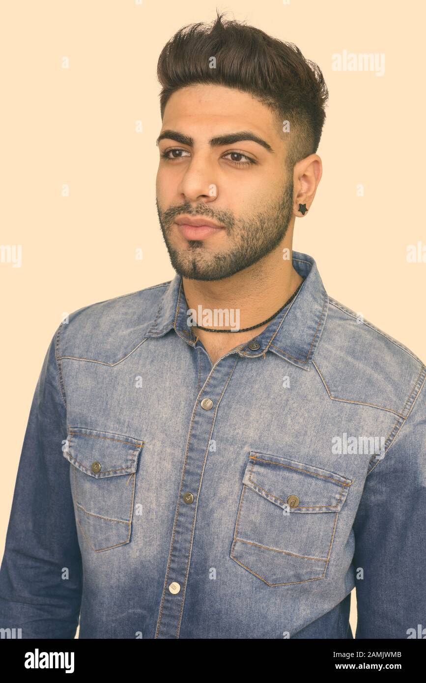 Studio shot of young handsome bearded Indian man isolated against white ...