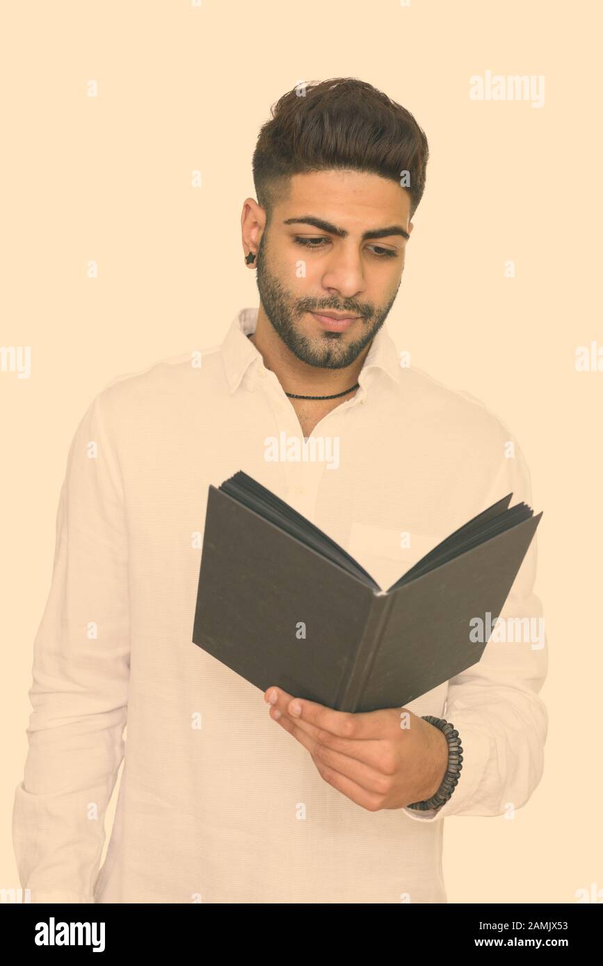Studio shot of young handsome bearded Indian man isolated against white ...