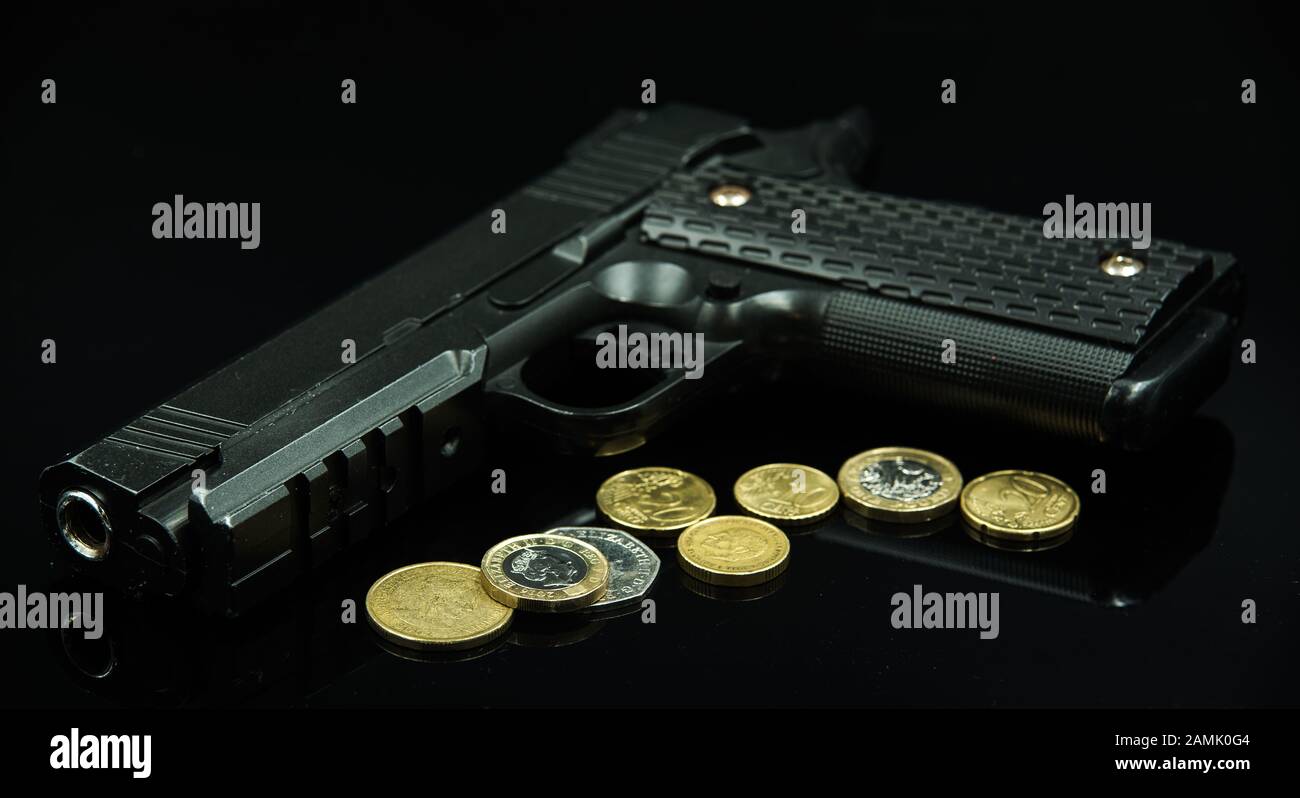 Gun and coins on black background Stock Photo - Alamy