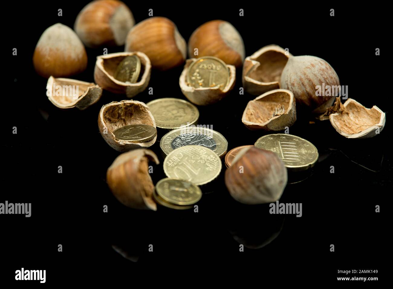 Nut shells and coins on black background Stock Photo - Alamy