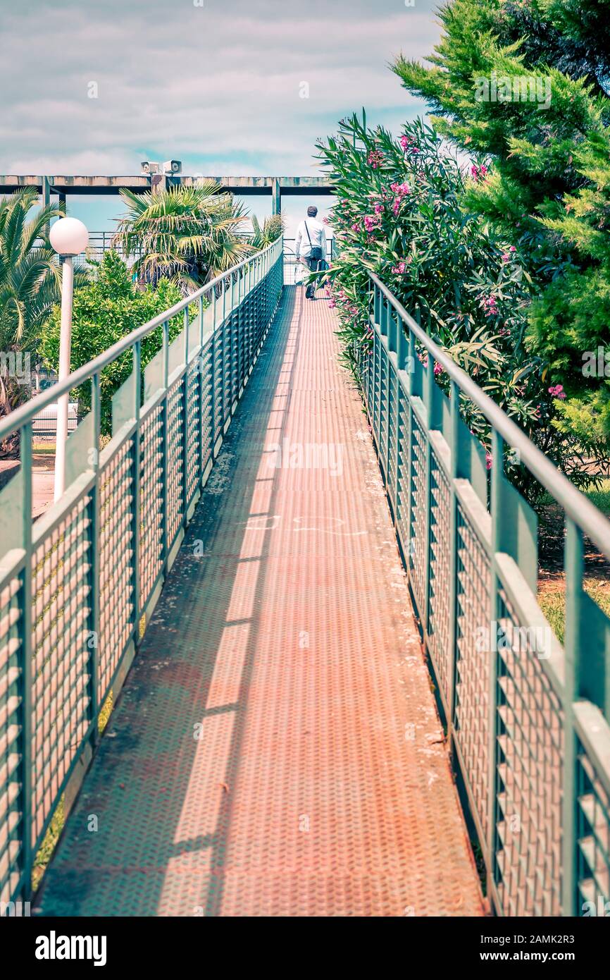 view of a man in a white shirt climbing the slope of a steel bridge ...