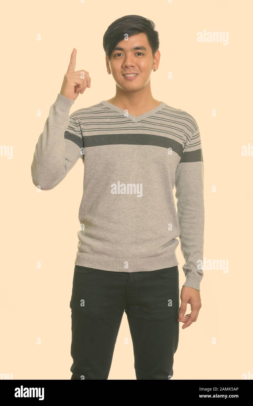 Studio shot of young handsome Filipino man isolated against white ...