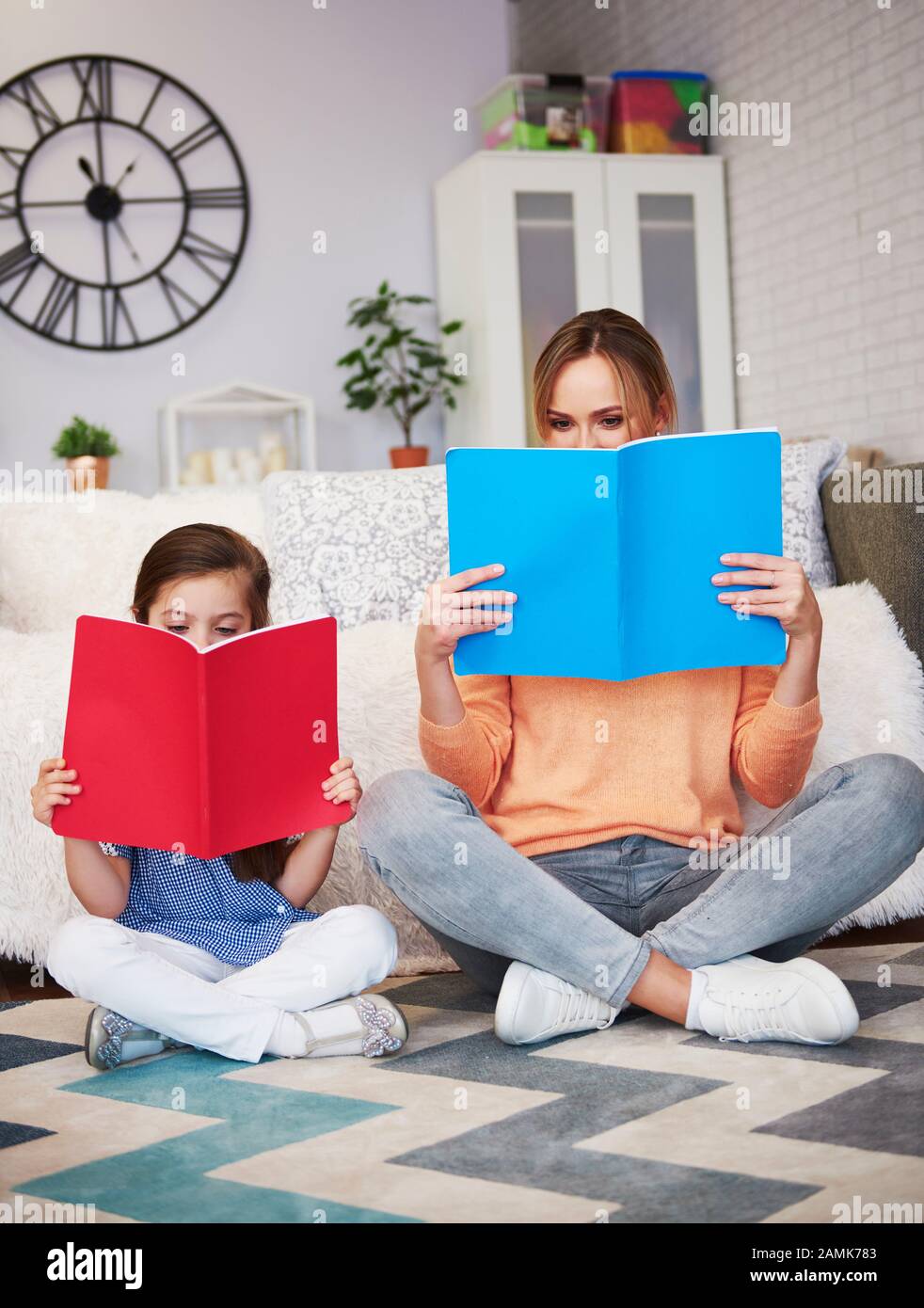 Mom and child reading a book in living room Stock Photo - Alamy