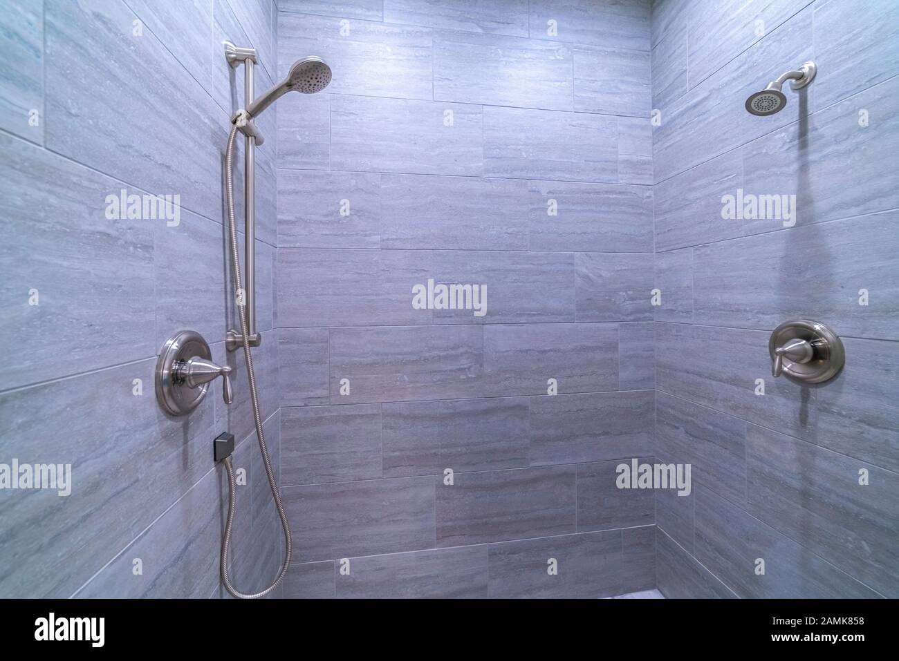 Tiled shower cubicle with dual heads bright interior Stock Photo - Alamy