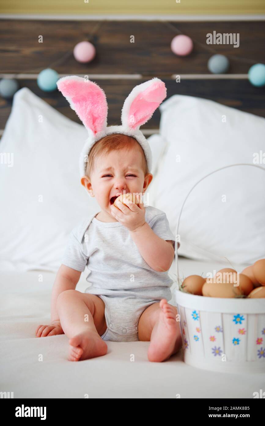 Crying baby eating an egg in bed Stock Photo - Alamy