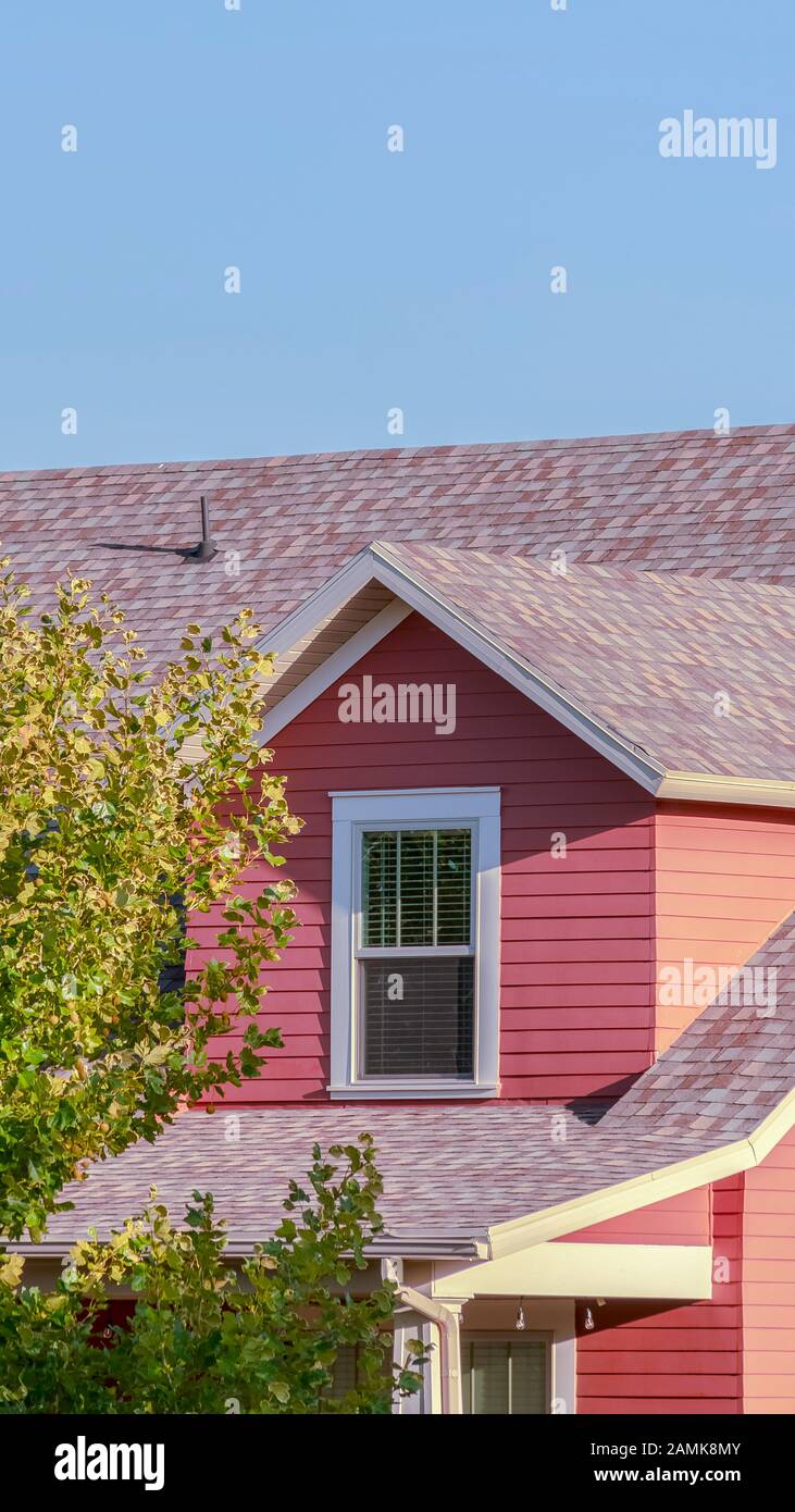 Vertical Colourful red timber clad house in green trees Stock Photo - Alamy