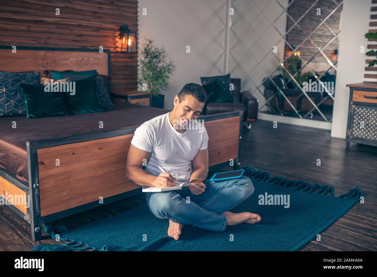 Cute smiling guy writing down a credit card number Stock Photo - Alamy