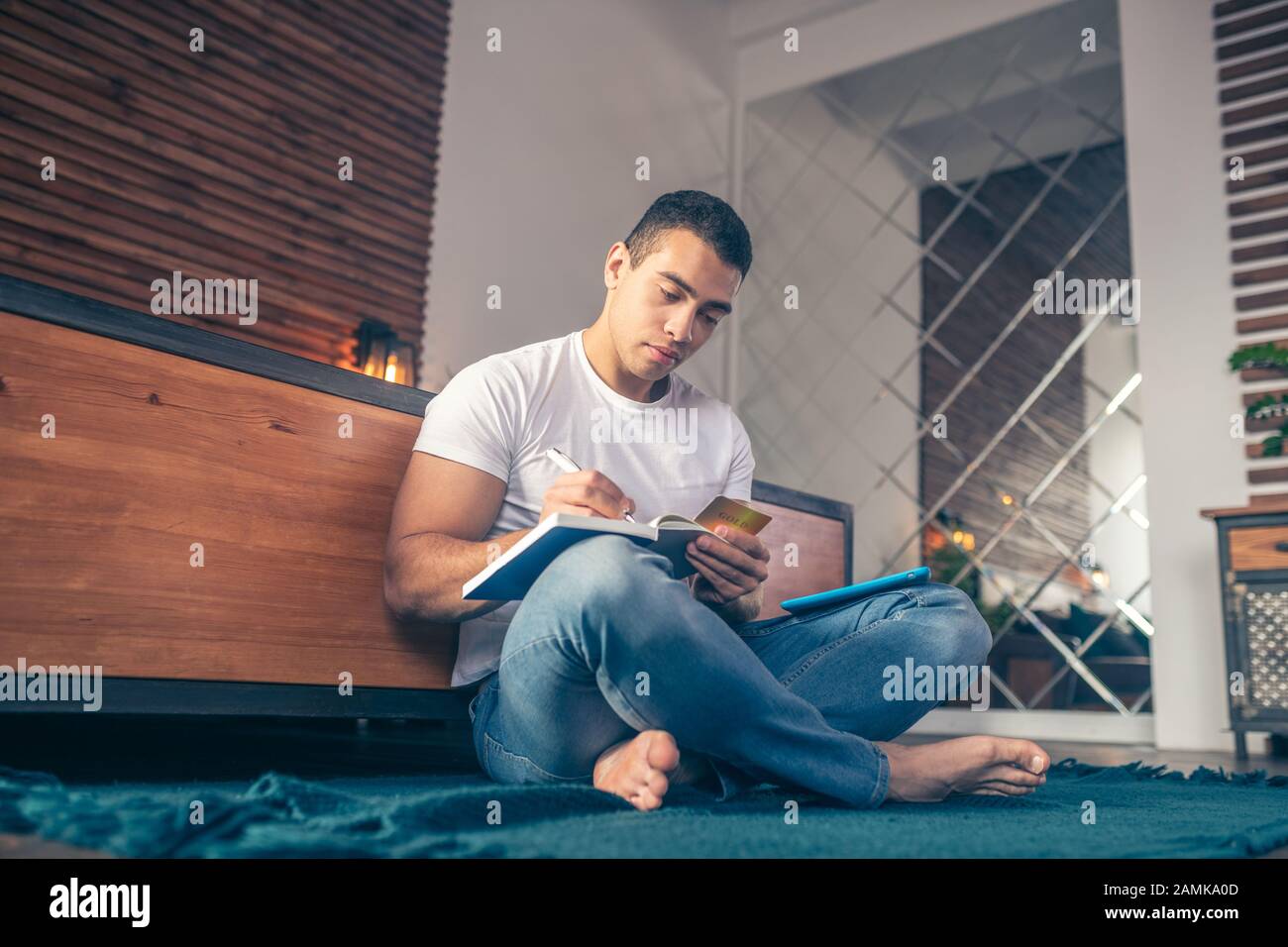 Guy sitting on the floor writing in a notebook Stock Photo - Alamy