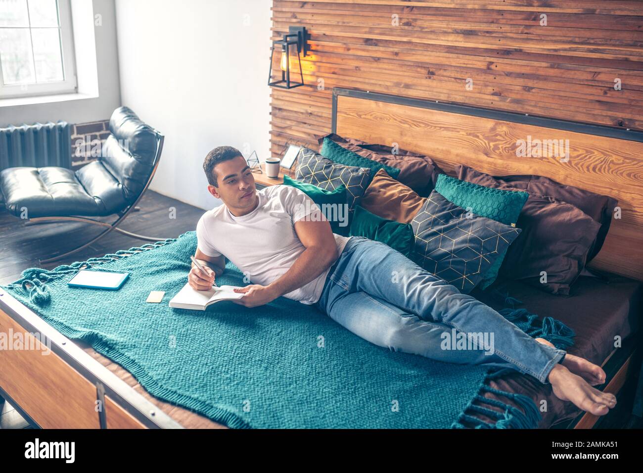 Muscular guy thinking while lying on the bed Stock Photo - Alamy