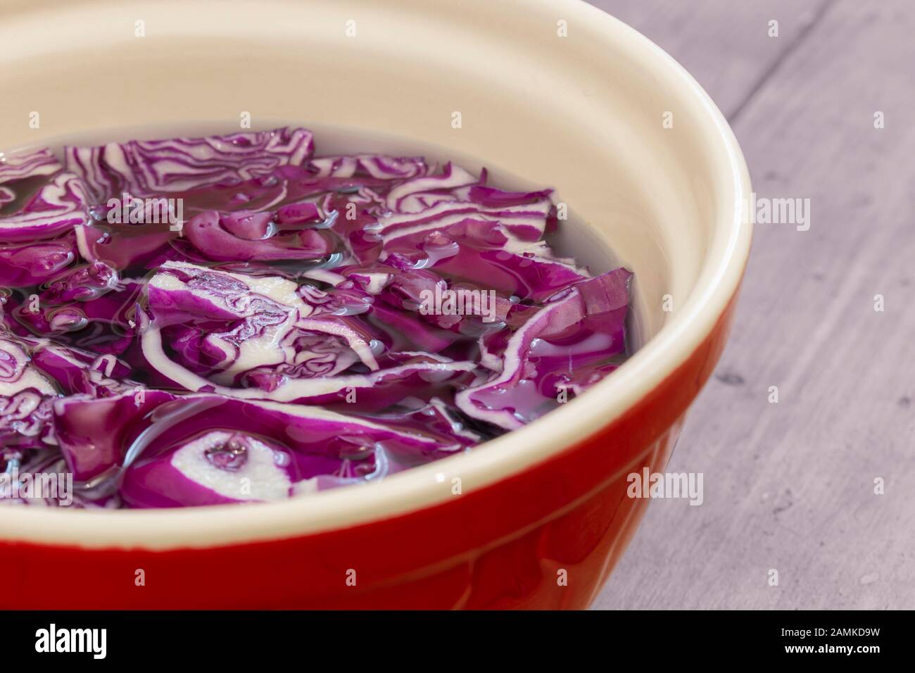 Sliced red cabbage soaking in water in a ceramic bowl. With a wood ...