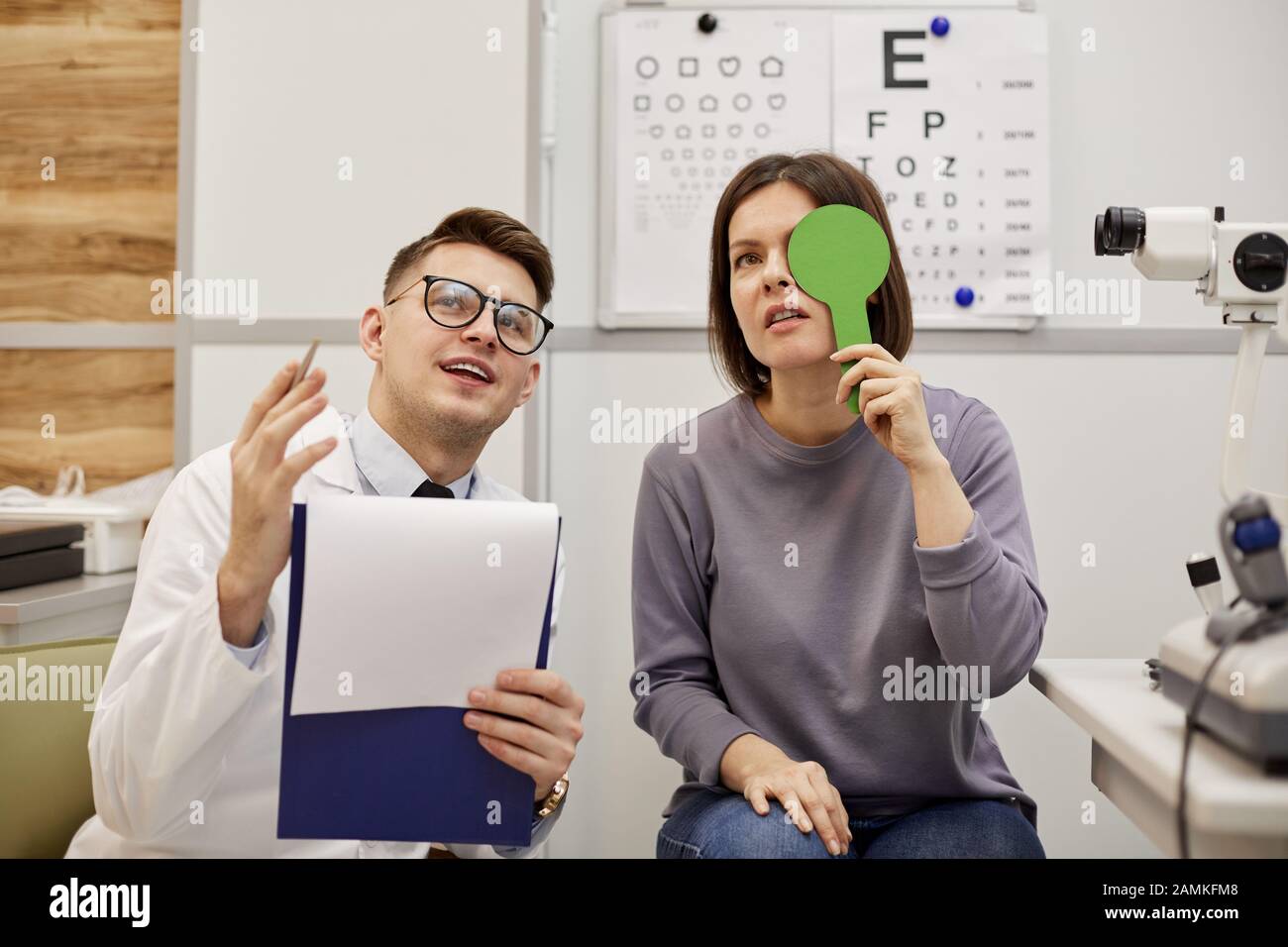 Portrait of young woman closing one eye during vision test in modern ... Portrait of young woman closing one eye during vision test in modern ...