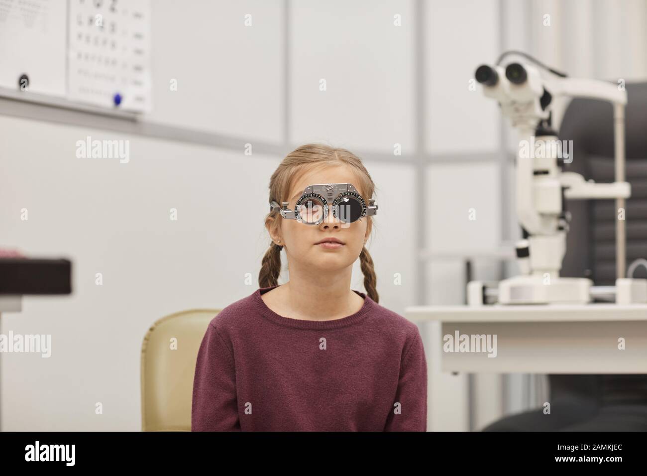 Portrait of cute little girl wearing trial frame during vision test in ...