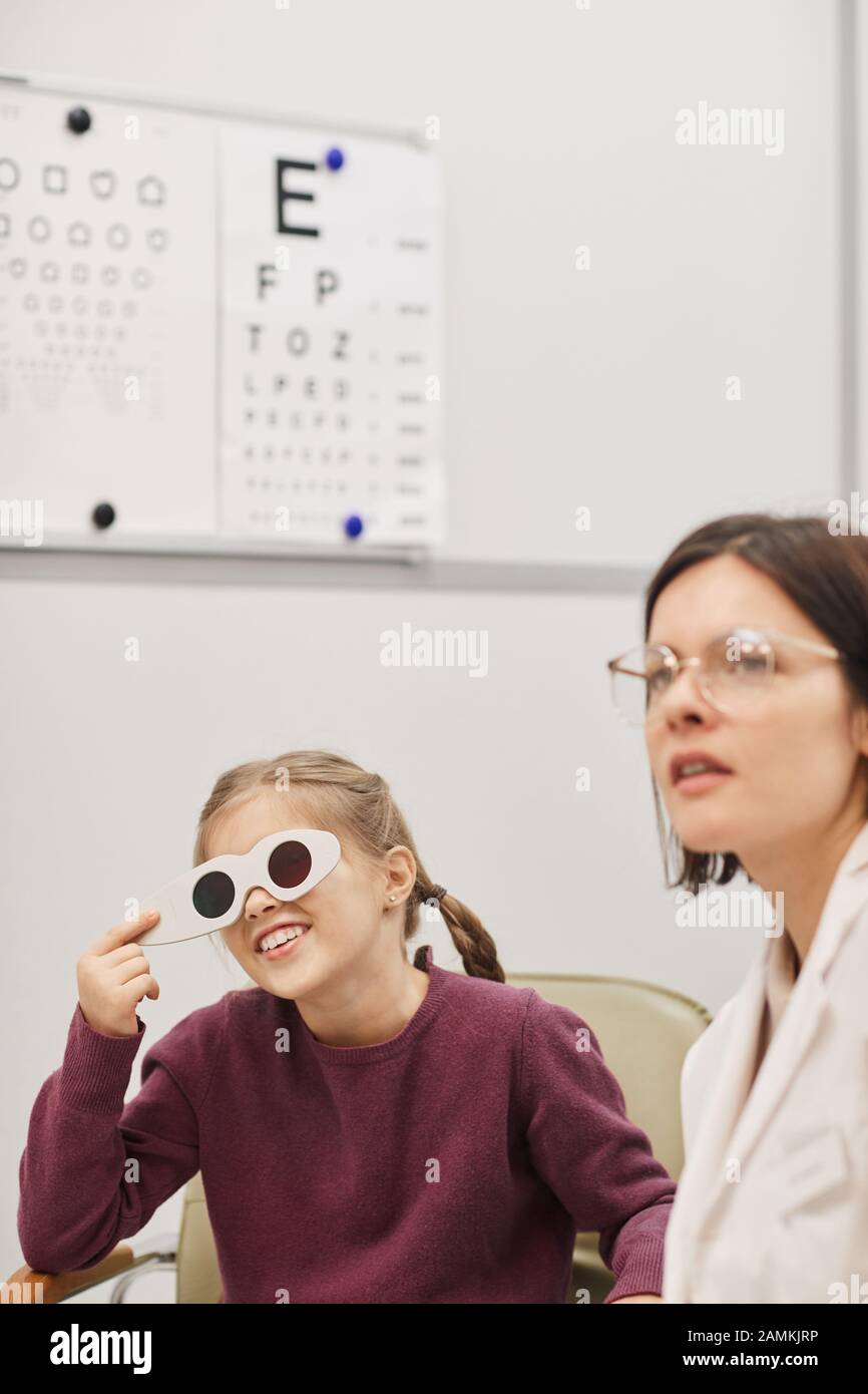 Portrait of cute little girl reading vision chart during eyesight test ...