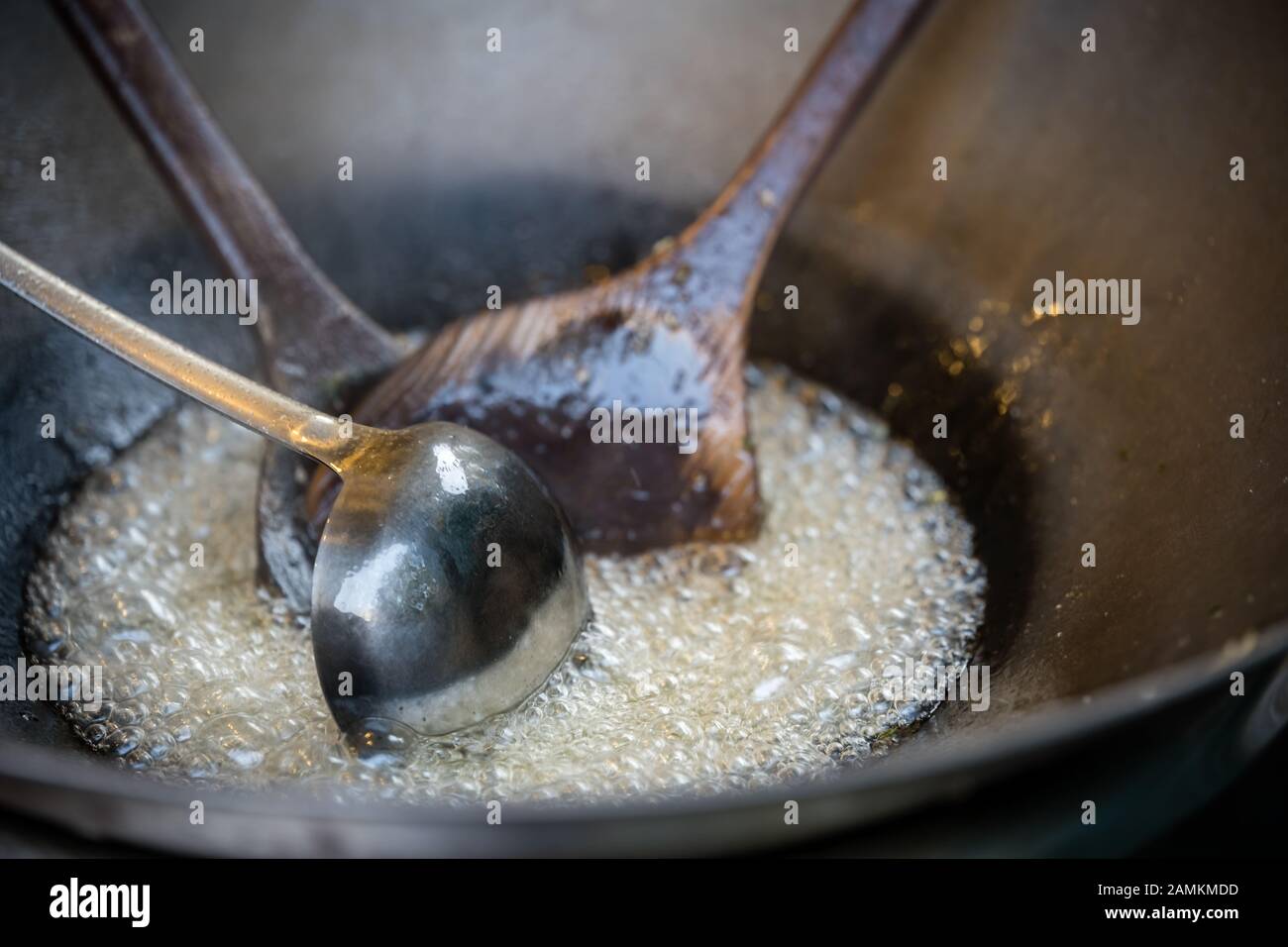 Three large ladles inside a metal pan full of hot boiling oil on a ...
