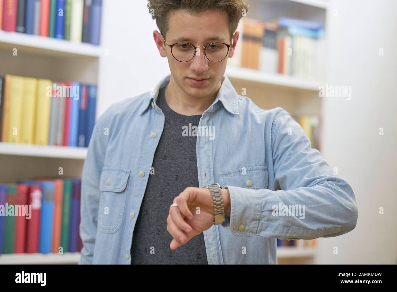 Portrait of a young man in library, lost in thought after he checked ...