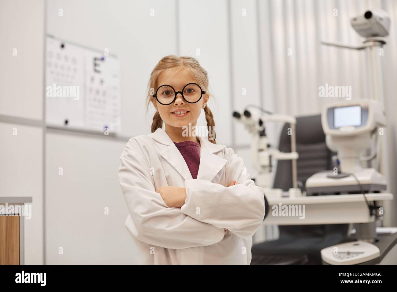 Waist up portrait of cute girl wearing lab coat and glasses smiling at ...