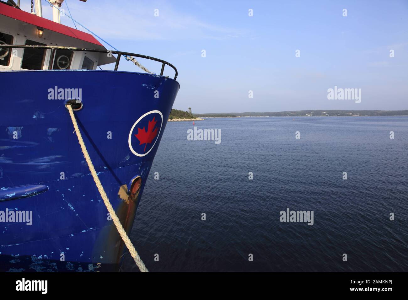 Ship with Canadian flag on the bow in the port of Sambro, Nova Scotia ...
