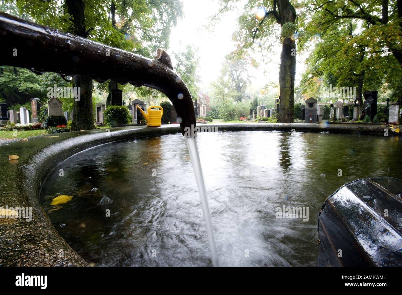Water ripples into a basin in the autumnal Ostfriedhof cemetery. On the ...