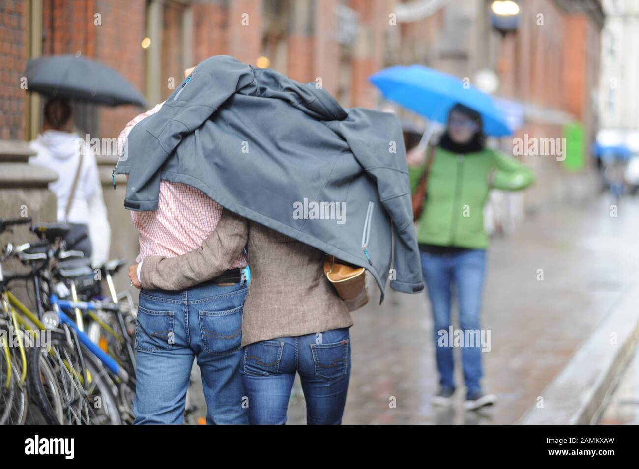 A couple protect themselves from the rain in the centre of Munich with ...