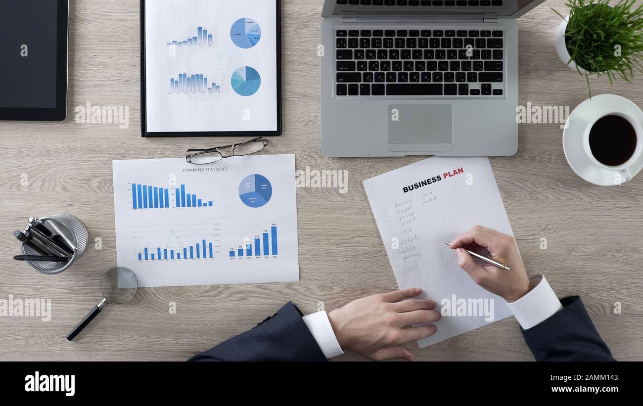 Business person making notes in their business plan, writing down new ...