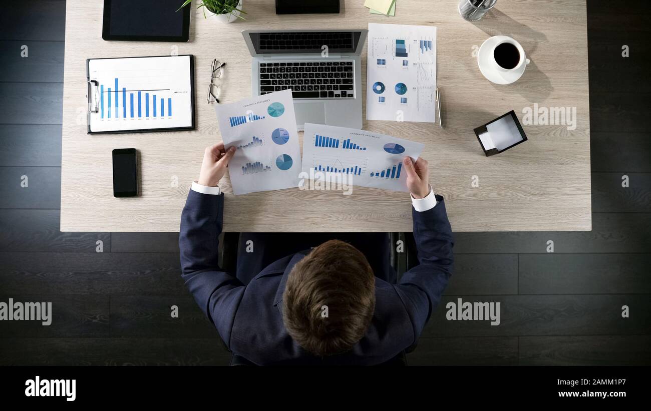 Manager comparing company statistics with head office data on laptop ...