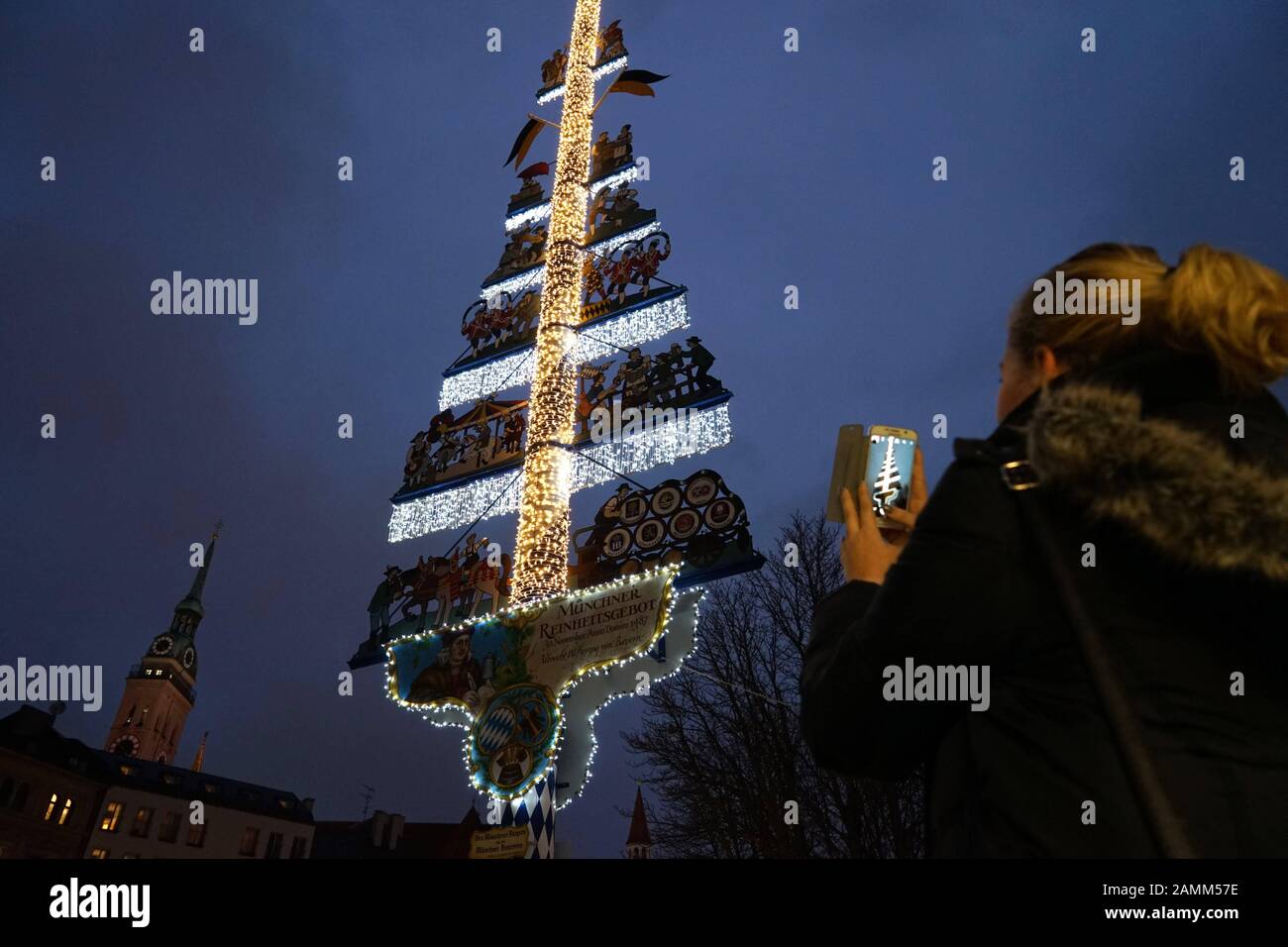 A woman takes a photo of the maypole decorated with Christmas lights at ...