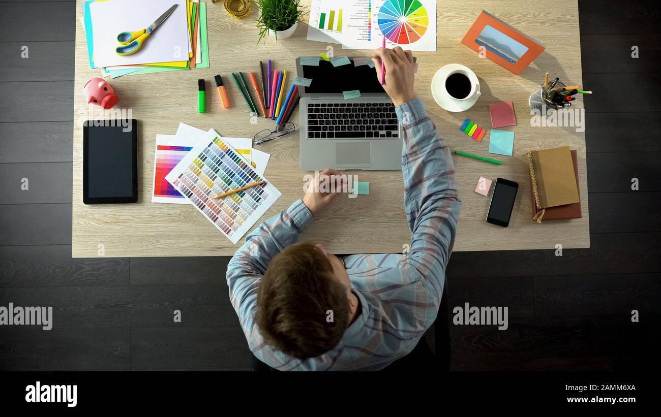 Male creator writing down his goals and plans on stickers and putting ...