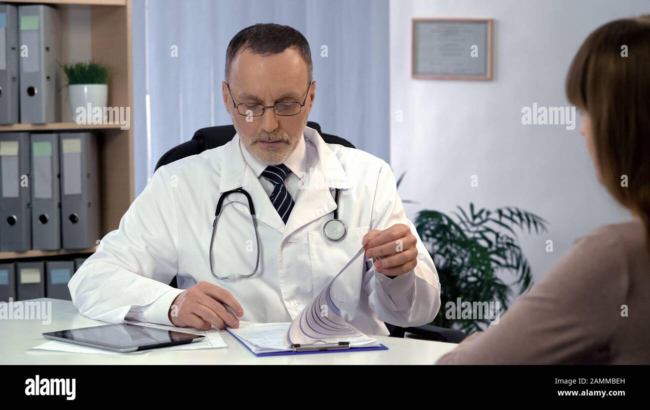 Doctor reading registration form, checking analysis, telling diagnosis ...