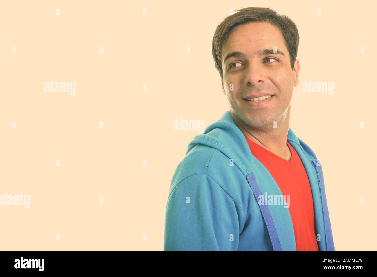 Close up of young happy Persian man smiling while thinking and looking ...