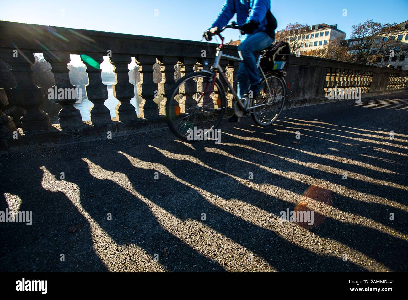 A cyclist rides on the shadow of the railing of the Luitpold Bridge in ...