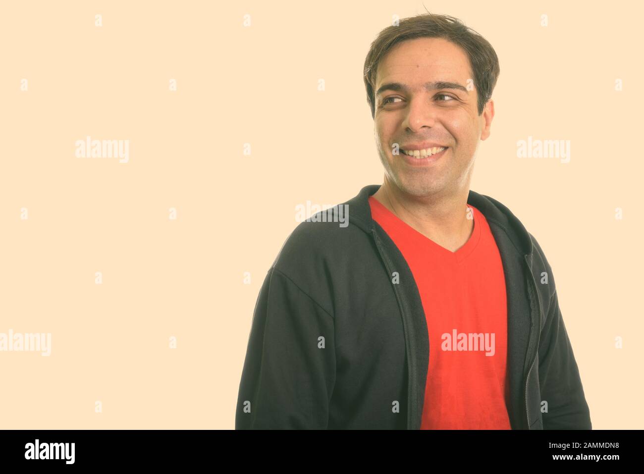Close up of young happy Persian man smiling and thinking while looking ...