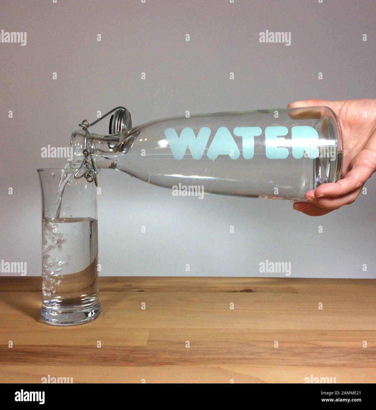 Water flows from a glass bottle with the inscription "Water" into a ...
