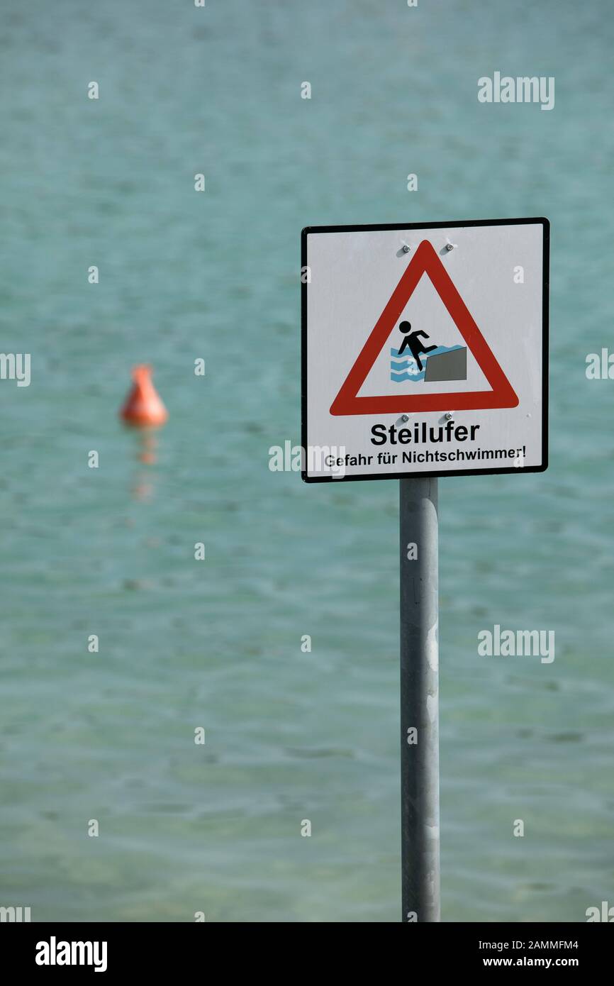 Signs point out the steep bank at Riemer See in the east of Munich. The ...