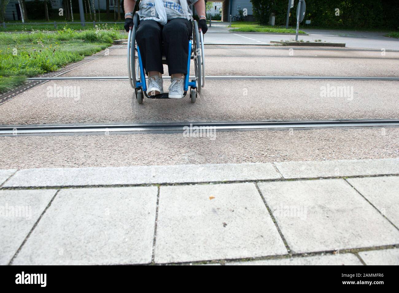 A disabled woman in a wheelchair crosses bumpy and inclined paths and ...