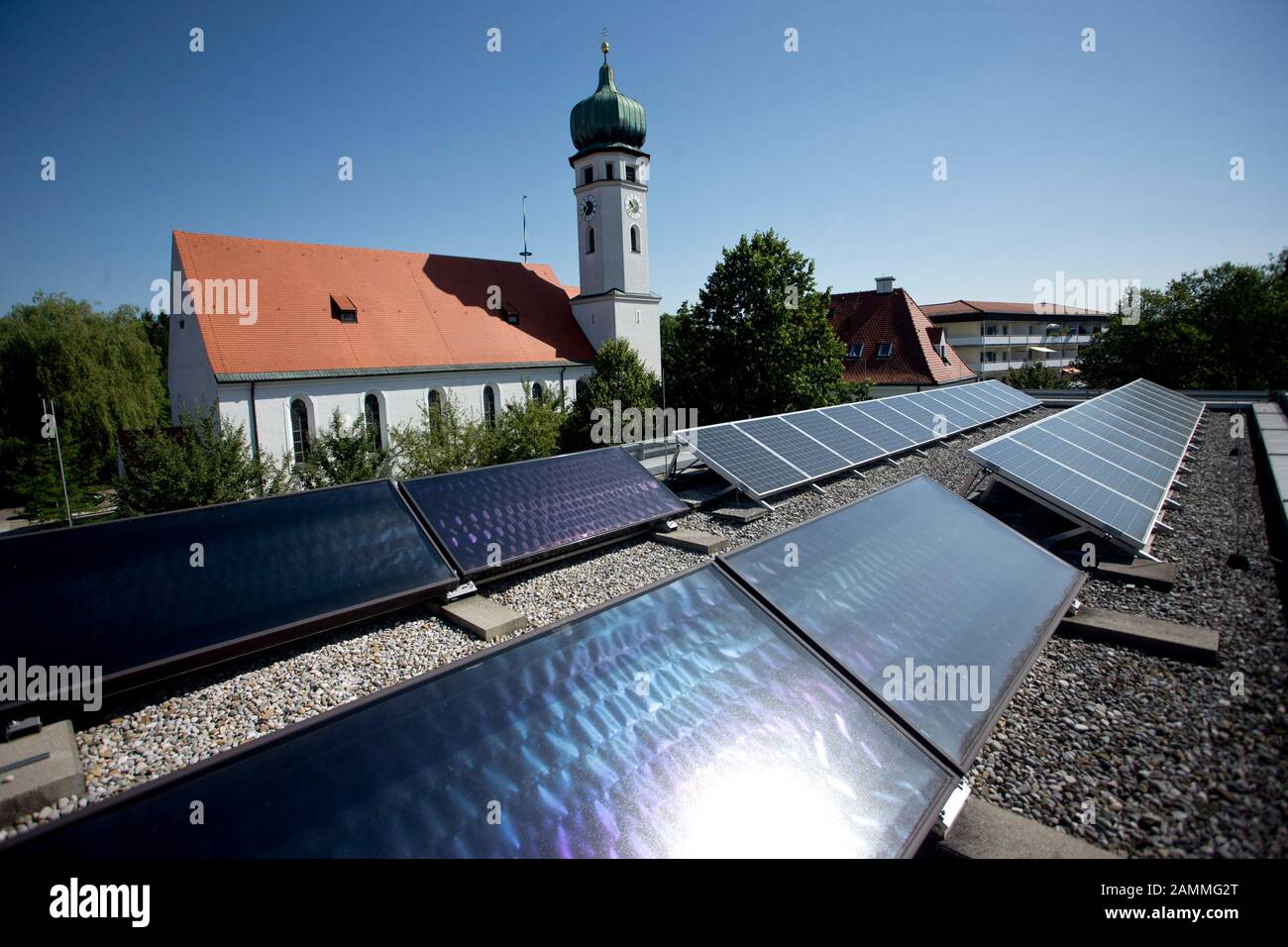 Photovoltaic system on a house roof, in the background a church ...