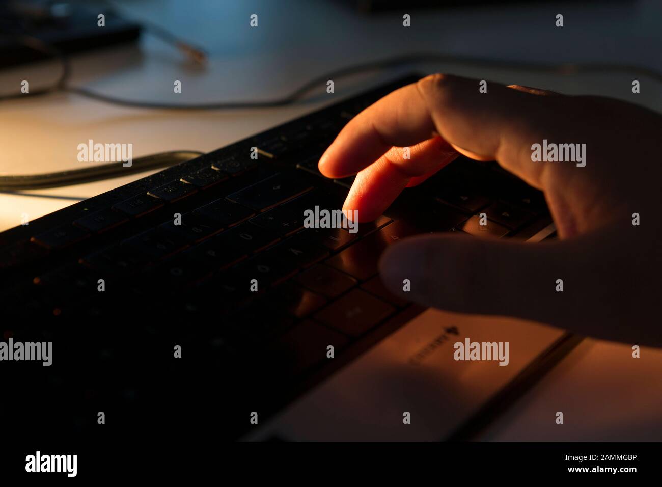 Symbol image for cybercrime: hands on the keyboard of a computer ...