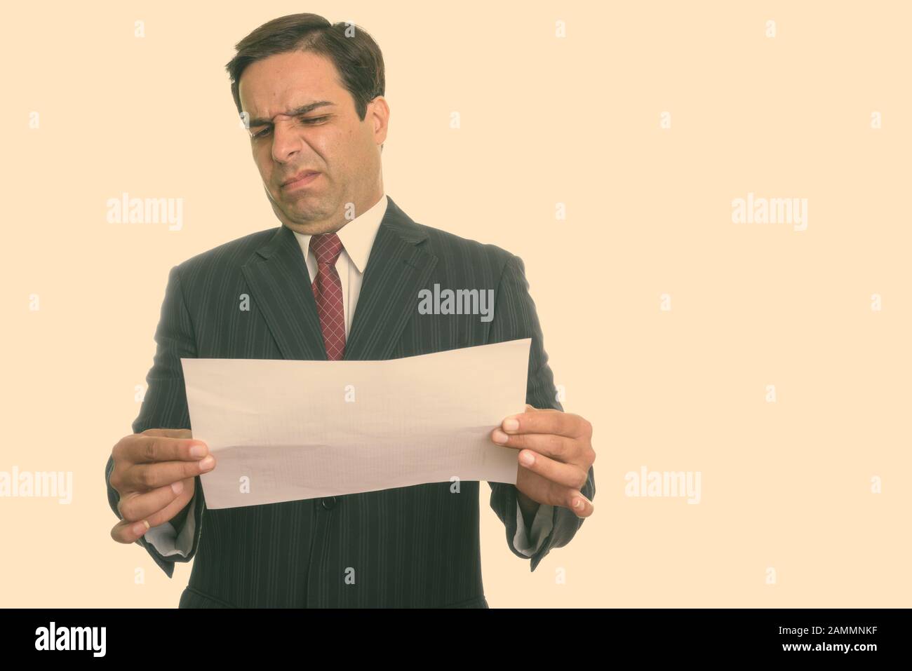 Studio shot of young Persian businessman reading on paper while looking ...