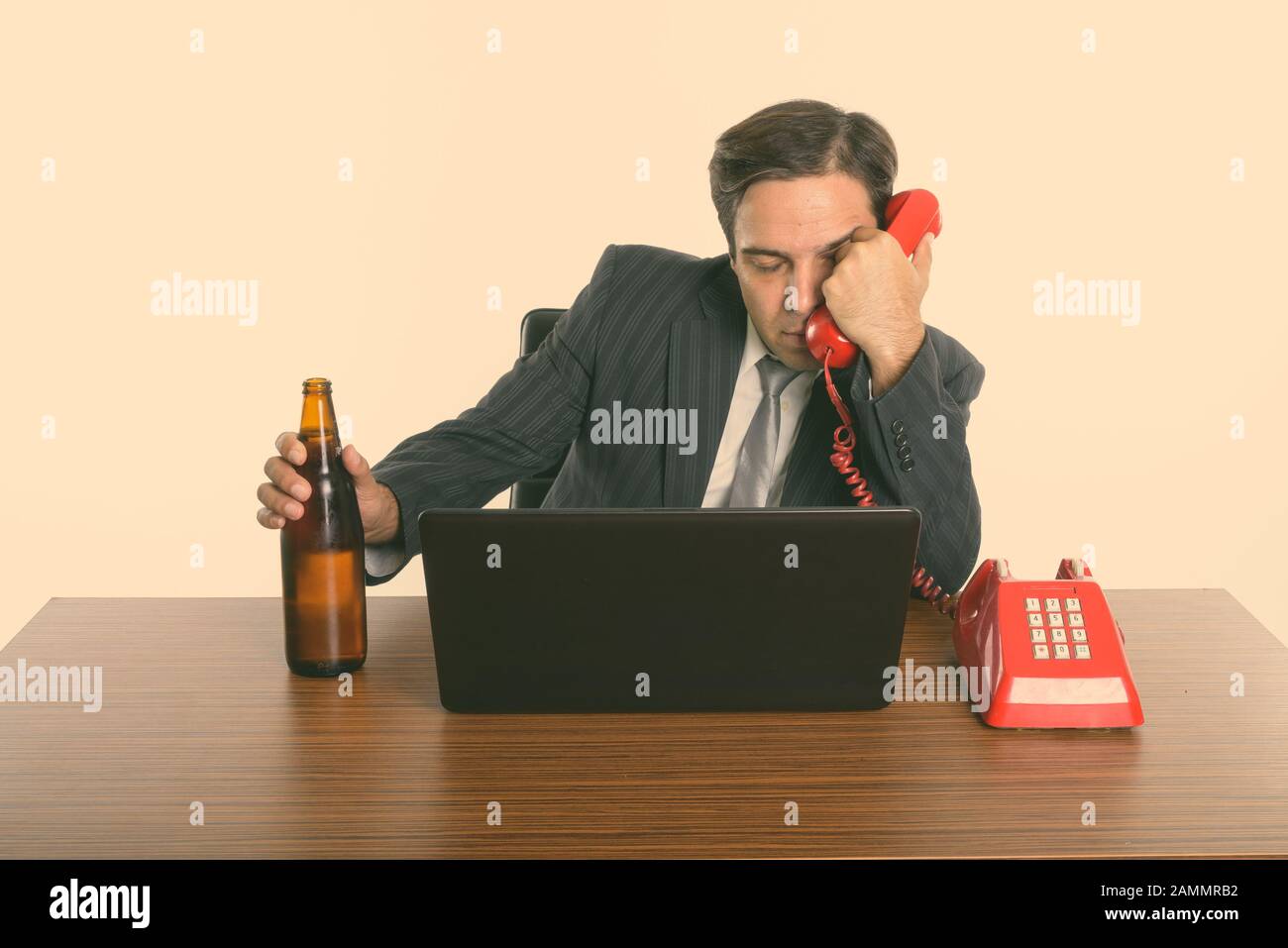 Drunk Persian businessman drinking beer while talking on old telephone ...