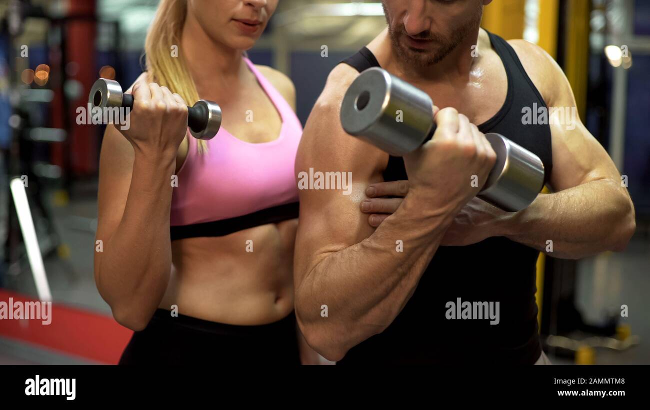 Trainer showing female trainee how to workout with dumbbells, healthy ...