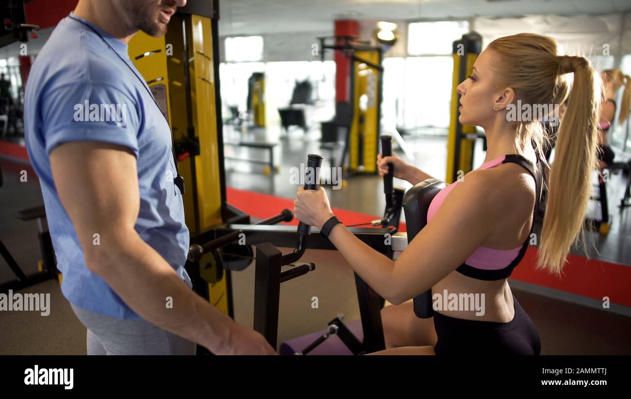 Fitness coach giving advice to his female client, teaching how to do ...