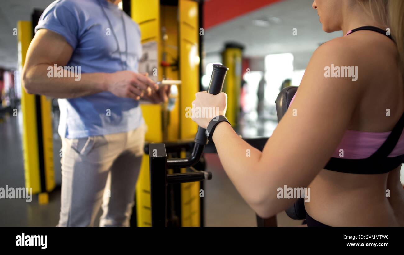 Fitness coach helping female client do exercises in gym, healthy ...