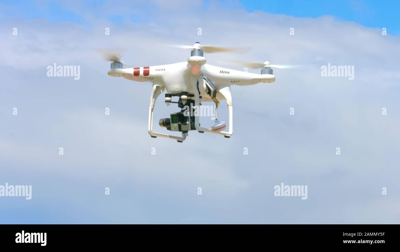 Quadrocopter with mounted camera flying in sky, filming video, modern ...