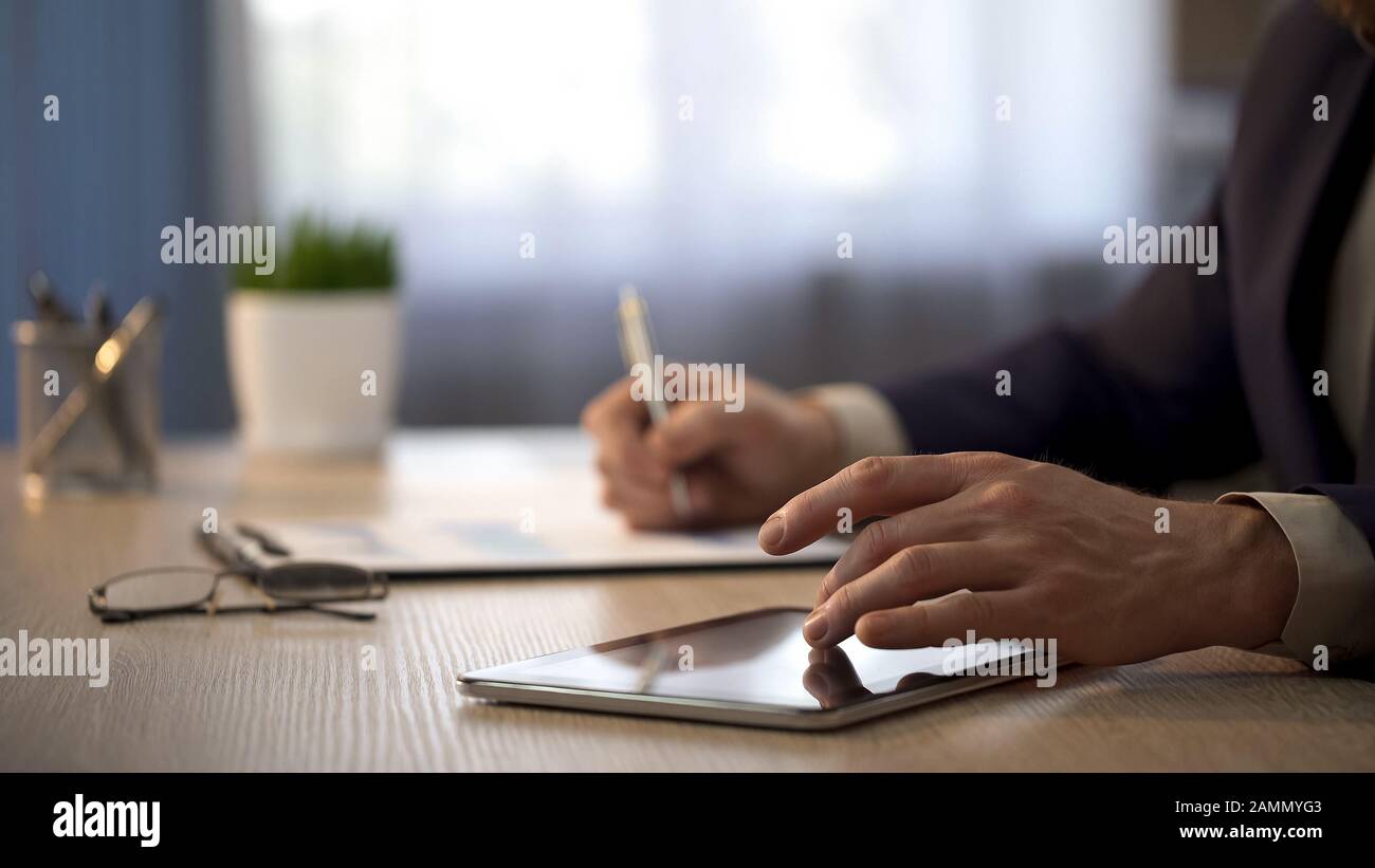 Employee comparing data on tablet and paper graphs, presentation of ...