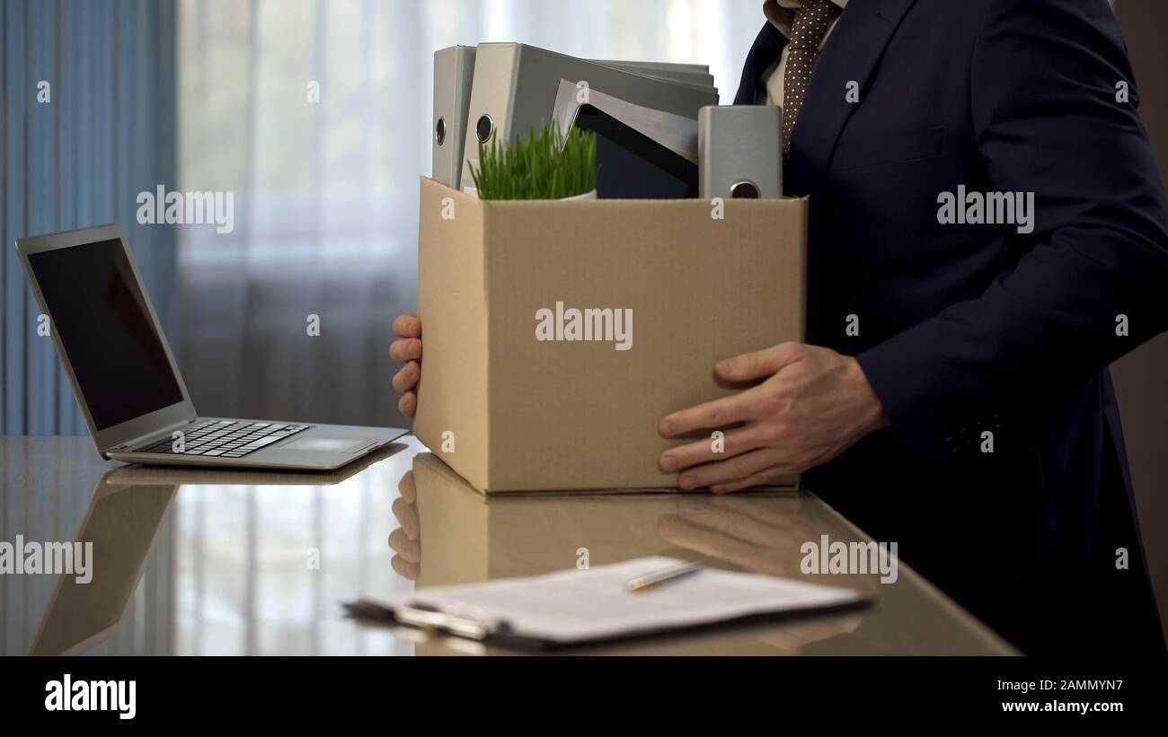 Employee putting his stuff from work desk in carton box, leaving job ...