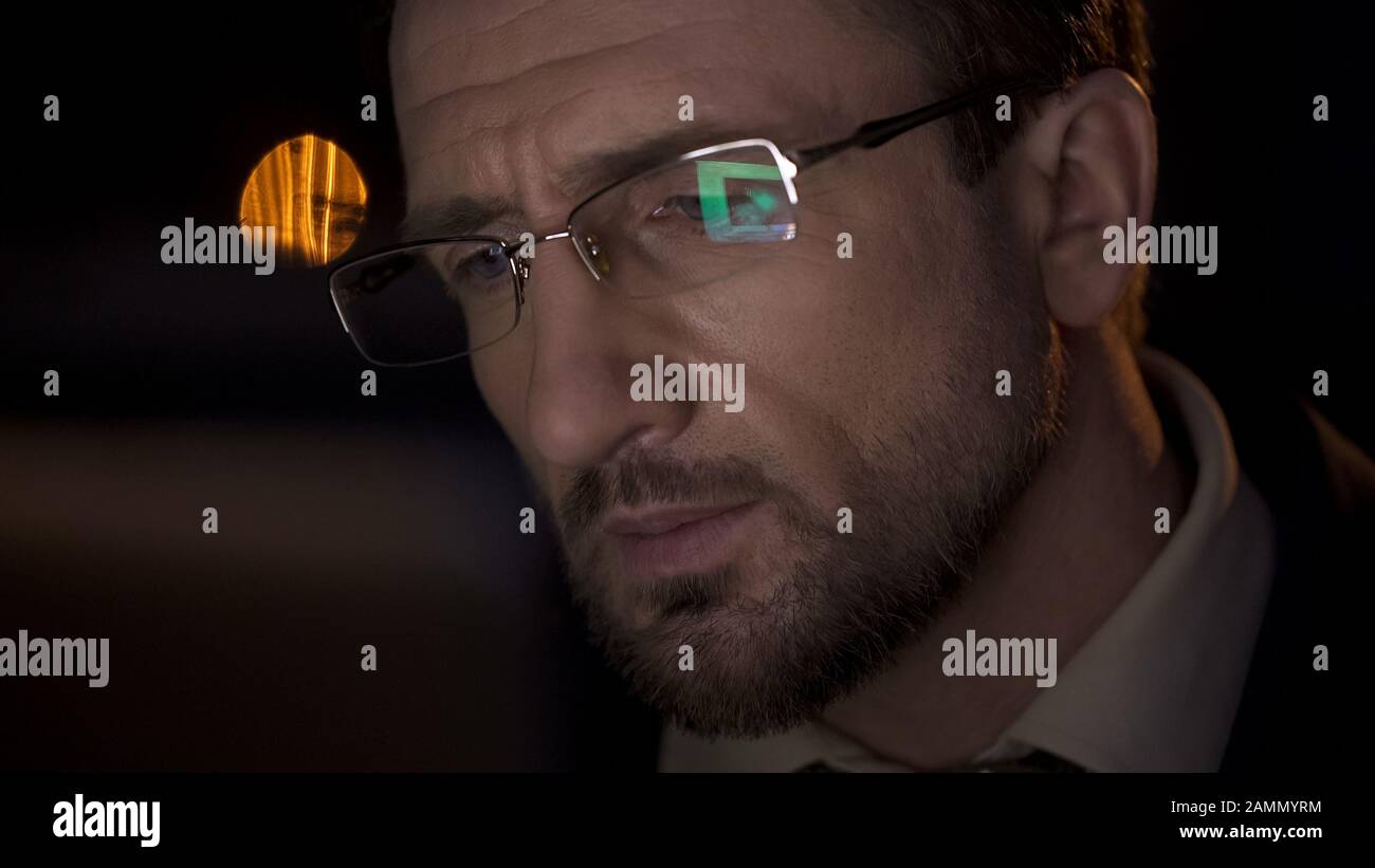 Closeup of detective face, male looking at PC screen reflected in his ...